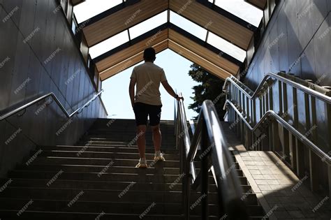 Premium Photo Young Man In A Tshirt And Shorts Climbs The Steps At
