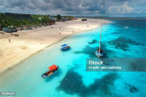 화창한 날에 모래 해변과 열대 바다 해안에 보트의 공중 보기 인도양 잔지바르 아프리카의 여름 휴가 보트 야자수 투명 한 푸른 물