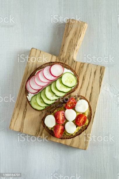 나무 도마에 야채 무 오이 체리 토마토와 어두운 빵 조각에 두 채식 샌드위치 흰색 나무 배경 플랫 평지 상단 보기에 중앙 구성