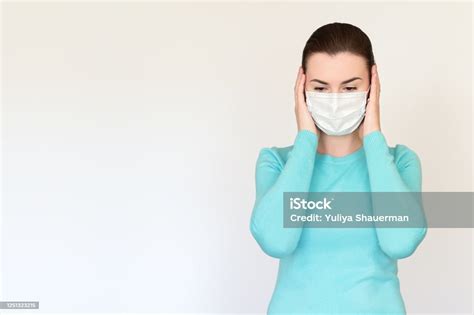 의료용 마스크를 쓴 한 여성이 머리를 손에 들고 아래를 내려다본다 흰색 배경에 촬영 전염병 공황 개념 감기와 독감에 대한 스톡 사진 및 기타 이미지 Istock