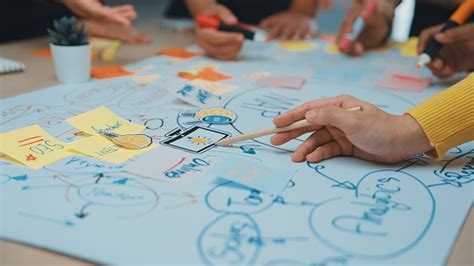 현대적인 사무실 공간 Sactr에서 큰 종이에 다채로운 스티커 메모로 프로젝트 아이디어에 대해 브레인스토밍하고 협업하는 사람들의 그룹 개념에 대한 스톡 사진 및 기타 이미지