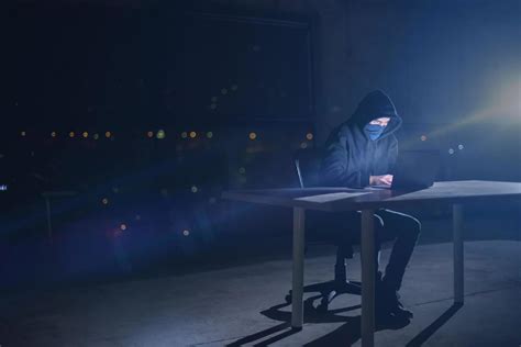 hacker using laptop computer while working in dark office 12442948