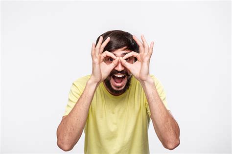 흰색 배경 위에 고립 된 두 손으로 Ok 기호의 제스처를 보여주는 노란색 셔츠에 콧수염을 가진 잘 생긴 브루넷 수염 남자 확인 제스처 T 셔츠에 대한 스톡 사진 및 기타