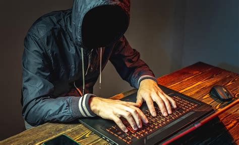 Premium Photo A Hacker Anonymous In A Hood Is Typing On A Laptop