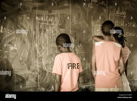 Three Young Students Write On A Blackboard In A Classroom Hell Ville School Madagascar Stock