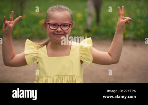 Girl With Down Syndrome Wearing Pink Glasses And Yellow Dress Smiles