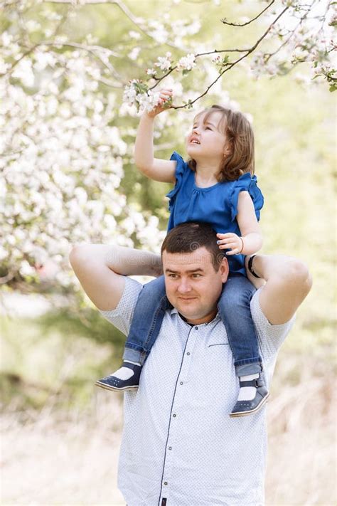 Father Playing With His Daughter In The Park Daughter Sitting On