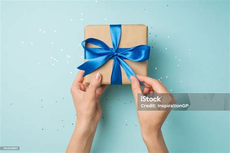 고립된 파스텔 블루 배경에 반짝이는 스팽글 위에 선명한 파란색 사틴 리본 리본 리본이 달린 수제 종이 기프트박스 1인칭 탑 뷰 사진 선물에 대한 스톡 사진 및 기타 이미지