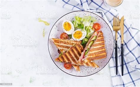 햄 토마토 치즈 아보카도 커피 한 잔을 곁들인 클럽 샌드위치 파니니구이 맛있는 아침 식사 또는 간식 상단 보기 플랫 레이 파니니