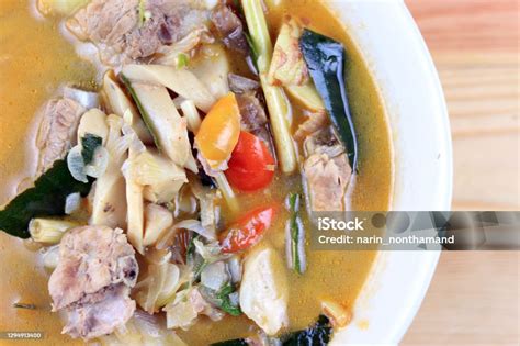 매운 삶은 돼지 고기 뼈와 짚 버섯 야생 토마토 나무 테이블에 흰색 그릇에 톰 얌 수프에 허브 태국 스타일의 음식에 톰 얌 수프 돼지 고기 건강한 생활방식에 대한 스톡 사진