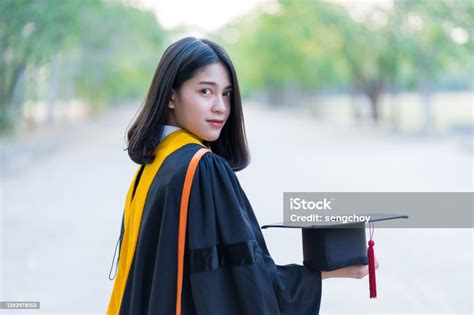 대학원 모자를 들고 학술 가운을 입고 젊은 쾌활한 여성 졸업생의 초상화는 대학 캠퍼스에서 시작 일에 그녀의 대학 학위를 축하합니다 교육에 대한 스톡 사진 및 기타 이미지