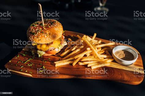 큰 샌드위치 육즙이 많은 쇠고기 버거 감자 튀김 토마토 나무 보드에 녹은 치즈를 곁들인 햄버거 0명에 대한 스톡 사진 및 기타 이미지 Istock