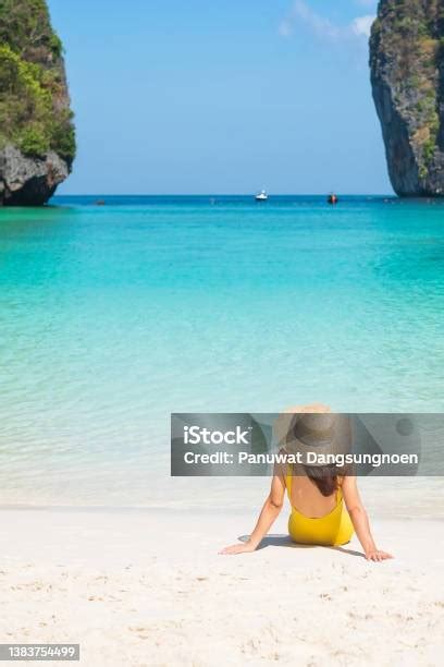 노란 수영복과 모자를 쓴 여성 관광객 태국 크라비 피 섬의 마야 베이 해변에서 일광욕을 즐기는 행복한 여행자 랜드마크 목적지 동남 아시아 여행 휴가 및 휴가 개념 노랑에