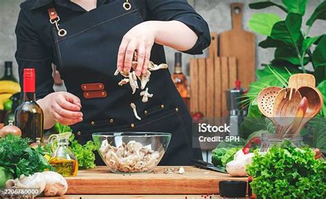 쿡은 유리 그릇에 느타리버섯을 붓습니다 나무 테이블 주방용품 야채 허브 요리 재료가 있는 아늑한 주방 건강한 비건 음식 요리 조리법 음식 블로깅 가정 생활에 대한 스톡 사진