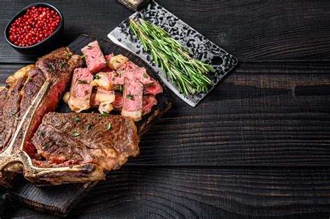 스테이크하우스 메뉴를 위해 얇게 썰고 구운 Tbone 또는 포터하우스 쇠고기 고기 스테이크 검은 색 나무 배경 맨 위 보기입니다 복사 공간 Steakhouse에 대한 스톡