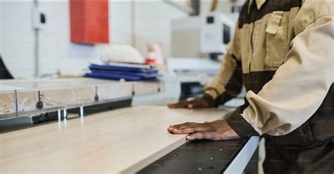 아프리카 장인이 가구 공장에서 작업하는 동안 기계에 나무 판자를 톱질하는 클로즈업 사진 Unsplash의 러시아 이미지