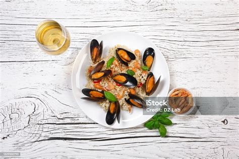 해산물 홍합 새우 바질이 달린 볶음밥 흰 금이 간 나무 테이블에 와인잔이 있는 접시 끓는 물에 삶기에 대한 스톡 사진 및 기타