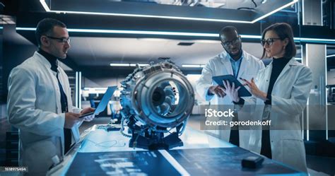 젊은 엔지니어 팀이 새로운 유형의 제트 터빈 엔진에 대해 협력합니다 태블릿 컴퓨터를 사용하고 과학 기술 공장의 혁신적인 기술을 설명하는 여성 프로젝트 리더 항공우주 산업에