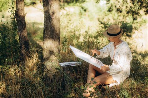 여름 방학에 공책에 메모를 하는 데 집중한 여자 야외에서 메모장에 펜으로 글을 쓰는 진지한 소녀 산에서 하이킹을 하는 동안 들판에 앉아 있는 젊은 여성 힙스터 그리기에 대한