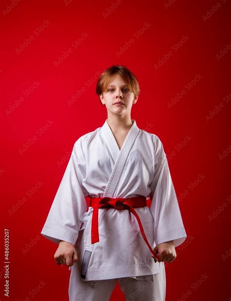 Young Girl Karateka In A White Kimono And A Red Belt Trains And