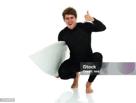 2029세 성인 잘생긴 남성젊은 남성이 흥분행복미소성공외침축하 를 받고 있는 잠수복수영복을 입고 흰색 배경 앞에 웅크리고 있는 남성전체 길이 20 24세에 대한 스톡 사진