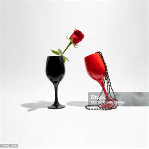 빨간색 Gerbera 데이지 꽃과 흰색 배경에 검은 진주 목걸이가 있는 검은색과 빨간색 와인 잔 최소 시즌 파티 개념 창조적 인 여름 사랑과 열정 아이디어 개념에 대한 스톡