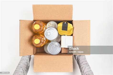 기부 상자에 음식을 수집하는 자원 봉사자 흰색 테이블에 식료품 제품이있는 골판지 상자를 들고 있는 탑 뷰 우먼 핸즈 기부 자선 푸드 뱅크 가난한 가족 이민자 난민에 대한