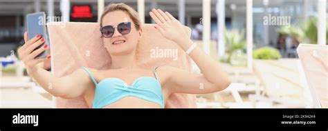 Young Blonde Woman Lay On Sunbed Wave Hi To Friend On Video Call Stock