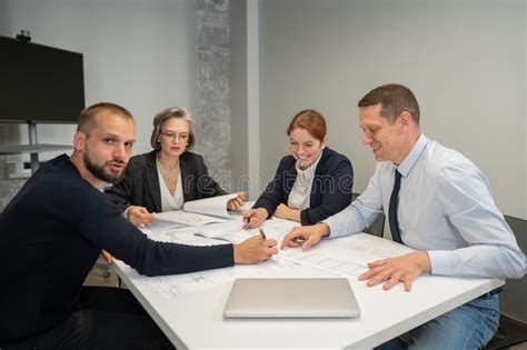 Four Colleagues Are Discussing Blueprints In A Conference Room In An Office Brainstorming Of