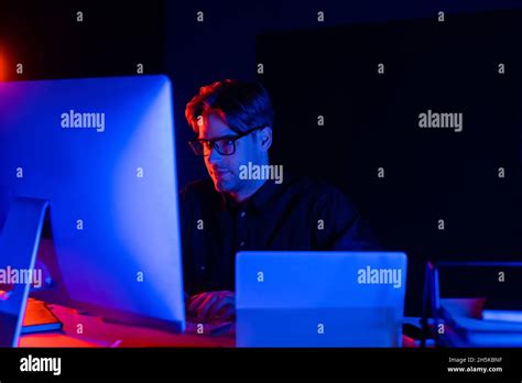 Young Programmer In Eyeglasses Using Computer Near Laptop On Black