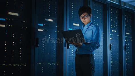 In Dark Data Center Male It Specialist Walks Along The Row Of Operational Server Racks Uses
