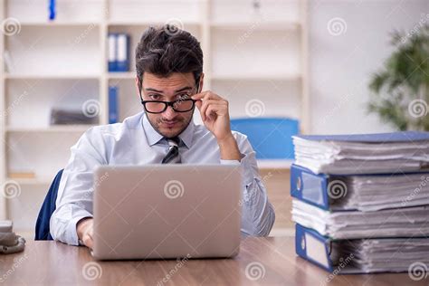 молодой сотрудник мужчина и слишком много работы в офисе Стоковое Изображение изображение