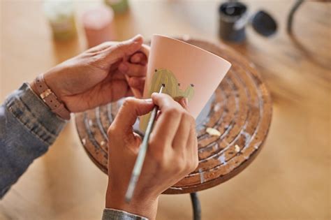 예술 중소기업 및 작업장에서 창의적인 제조 및 디자인을 위한 그림 컵 또는 머그잔의 근접 촬영 손과 예술적인 여성은 도자기 수업