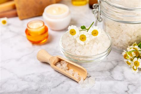 카모마일 스파 카모마일 꽃 수제 비누 에센셜 오일 화장품 병 바디 크림 스크럽 및 바다 소금이 흰색 질감 배경에 있습니다 편안한 뷰티 트리트먼트 복사 공간 건강관리와 의술에
