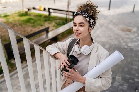 한 여성 젊은 성인 백인 여학생 배낭을 들고 서서 종이와 커피 한 잔을 들고 대학 건물 앞에서 밝은 날의 행복한 미소를 지으며 실제 사람들이 공간을 복사합니다 20 24세에