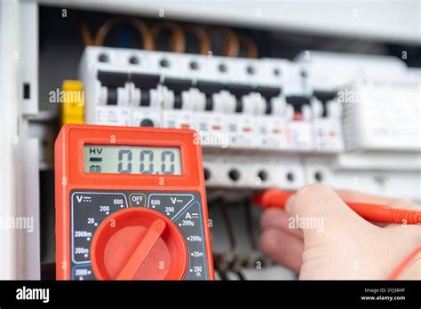 Electrician Measuring Voltage With Multimeter In Circuit Breaker Panel