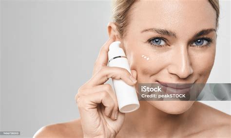 긍정적 인 백인 여성은 회색 배경에 얼굴에 보습 크림을 바르십시오 페이스 크림 보습 피부 스킨케어 노화 방지에 대한 스톡 사진 및 기타 이미지 Istock