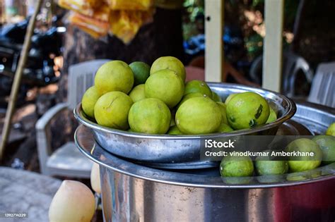 인도 마하라슈트라 콜하푸르의 여름철 길거리 주스 센터 또는 레몬 소다 카트 또는 센터의 강철 그릇이나 용기에 보관 된 신선한 육즙이 많은 노란색 레몬의 스톡 사진