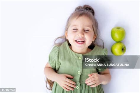귀여운 어린 소녀가 손에 큰 녹색 사과를 들고 있습니다 흰색 고립 된 배경입니다 어린이를위한 건강 식품 또는 건강한 간식 텍스트를 위한 공간입니다 고품질 사진 2 3 살에