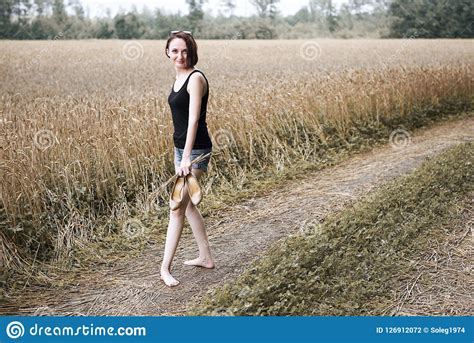 Young Girl Walking Barefoot On The Ground Road Through Field And Forest