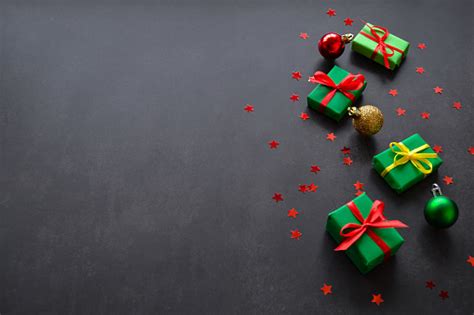 빨간색과 노란색 리본 금 빨간색과 녹색 크리스마스 공과 빨간 별의 형태로 색종이녹색 종이에 선물은 오른쪽에 있습니다 검은 색 배경 복사 공간 큰 판매 개념 개념에 대한 스톡