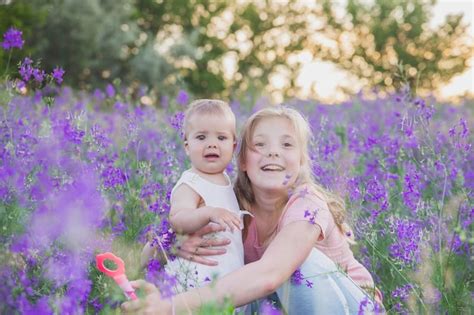 Premium Photo Two Blond Sisters In Flowers At Sunset