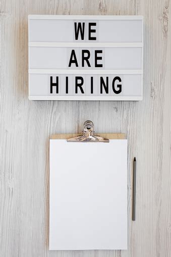 우리는 고용하고 있다는 단어들은 하얀 나무 배경에 빈 종이가 있는 클립보드 상단 보기입니다 오버 헤드 위에서 평평한 누워 구인 중에 대한 스톡 사진 및 기타 이미지 Istock