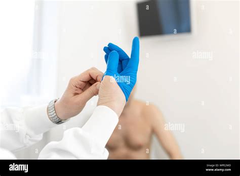 Doctor Urologist Puts A Medical Glove On The Arm To Examine The Patient