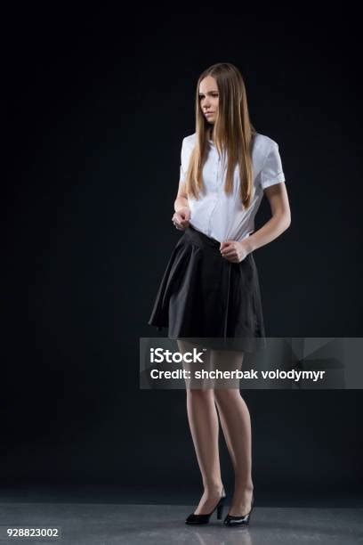 검은색 흰색 블라우스와 짧은 블랙 스커트 사무실 모습에 포즈에 십 대 소녀의 초상화 행복 한 학생 또는 검은색에 카메라 보고 긴