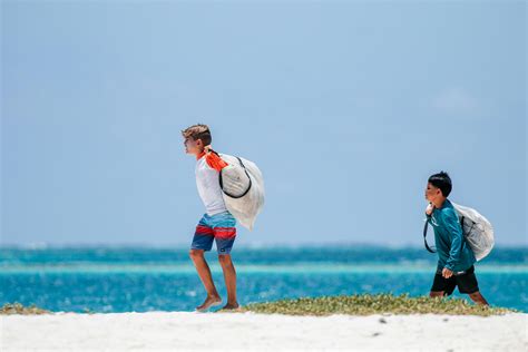 햇살 가득한 해변에서 맨발로 걷는 친구들 · 무료 스톡 사진