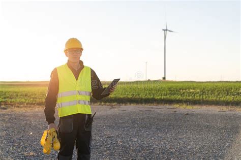 Engineer With Digital Tablet Works On A Field Of Wind Turbines Stock