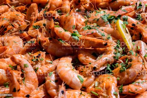 길거리 음식 축제에서 큰 팬에 토마토 소스와 녹색 파슬리와 함께 조리 된 새우의 큰 부분을 닫고 건강한 해산물 아름다운 오렌지 흑백 야외 배경을 먹을 준비가되셨습니다