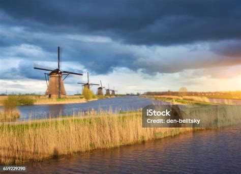 놀라운 풍차 물 운하와 푸른 흐린 하늘과 노란 햇빛 근처에 전통적인 네덜란드 풍차와 소박한 풍경 킨 더 다이크에서 화려한 일몰 봄에 네덜란드 흐린 하늘 0명에 대한 스톡