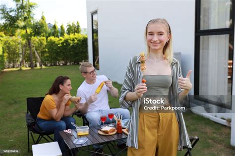 다양한 연령대의 행복한 가족이나 친구들이 바비큐를 만들고 적포도주 한 잔 옥수수 굽기 뒤뜰에서 엄지손가락을 치켜들고 미소를 지으며 바베큐 파티를 즐기며 야외에서 축하합니다